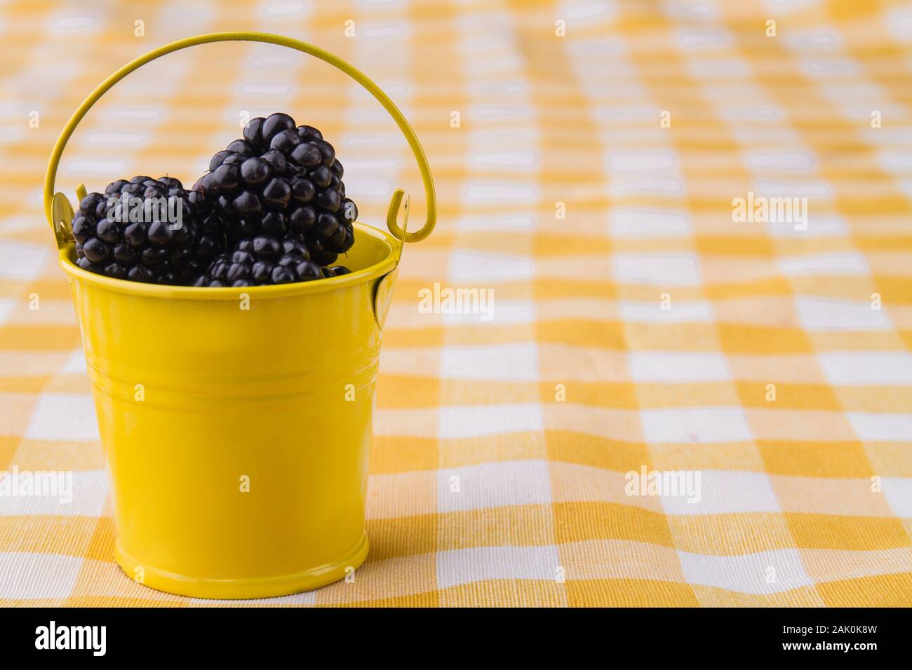 Tiny yellow bucket with blackberries Stock Photo - Alamy