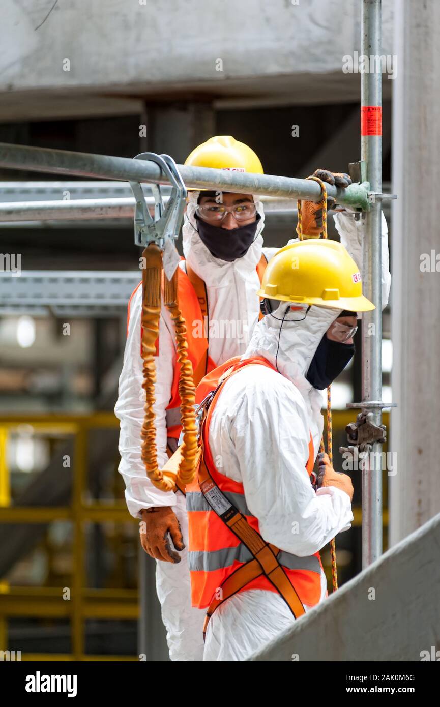 Workers in white protective uniform fixing pipes Stock Photo - Alamy