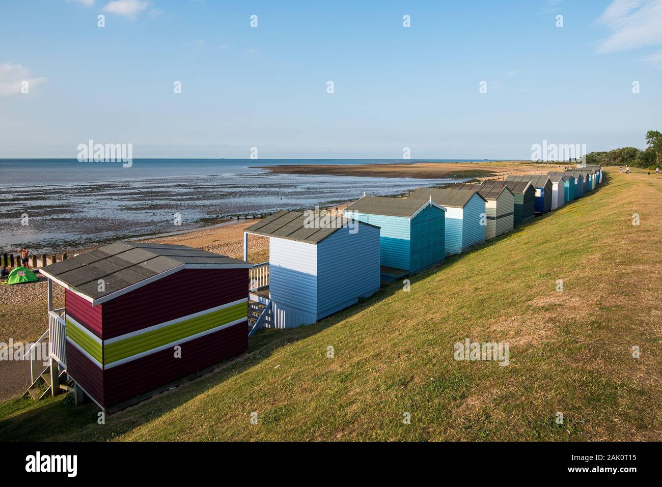 Multi-coloured holiday wooden beach huts facing the ocean on the beach ...