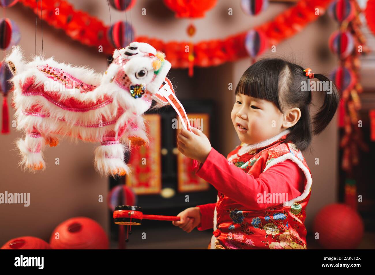 Chinese baby girl with traditional dressing up and holding dancing lion ...