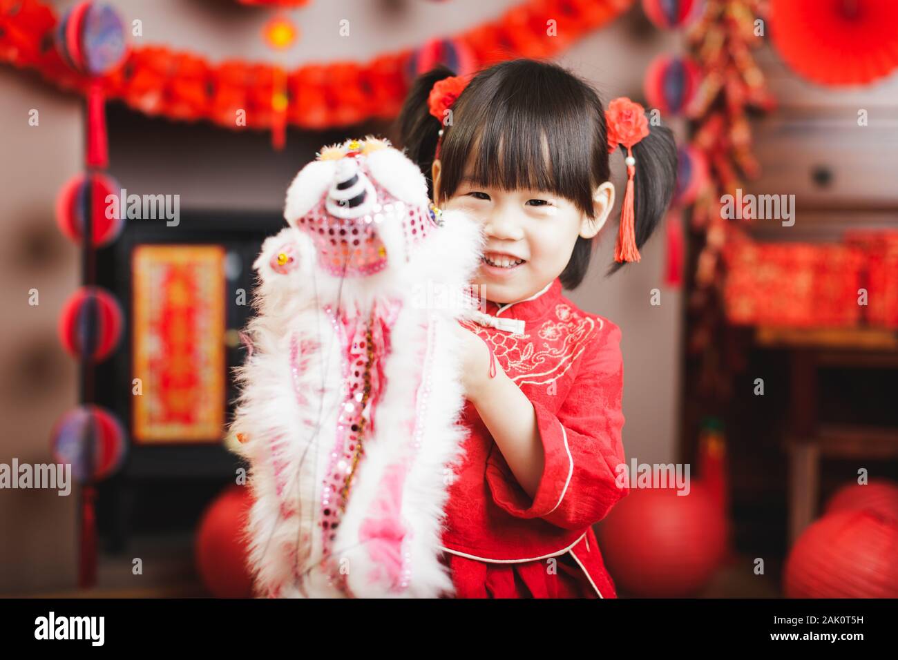 Chinese baby girl with traditional dressing up and holding dancing lion ...
