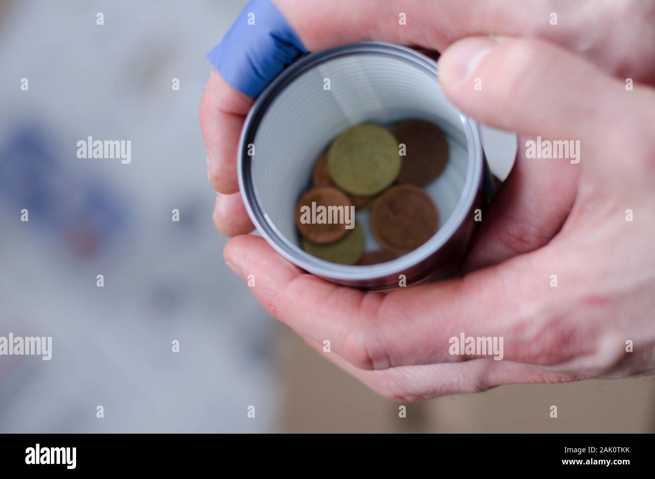 A person holding a cup with some coins begging for more change Stock ...