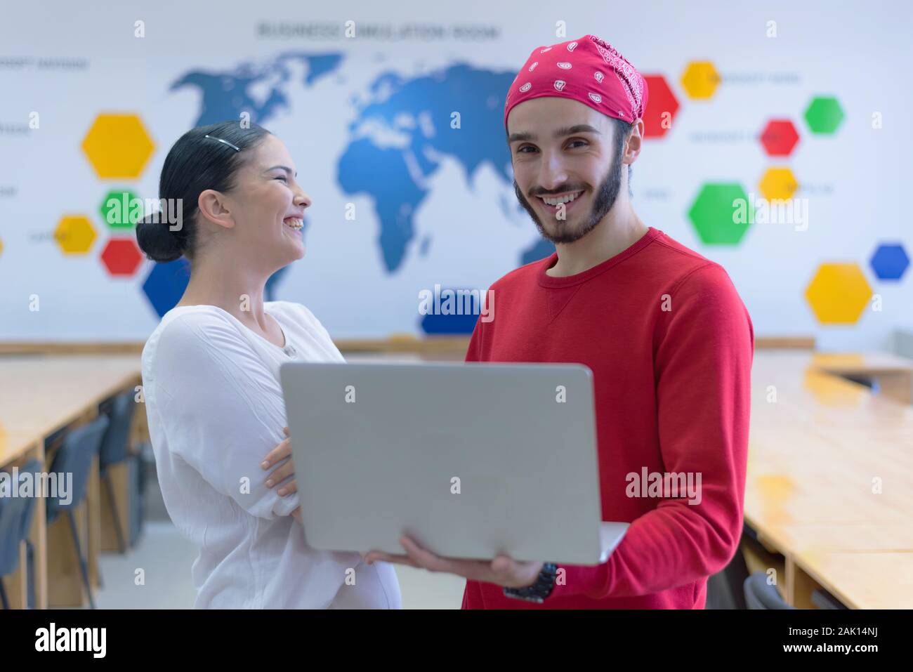 Two multietchnic college students standing inside classroom and using ...