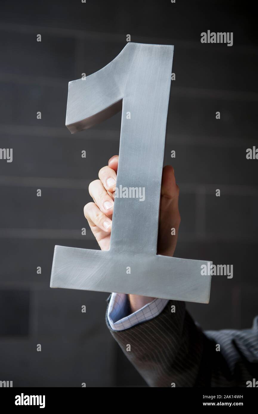 Hand of unrecognizable businessman holding a metallic silver Number One ...