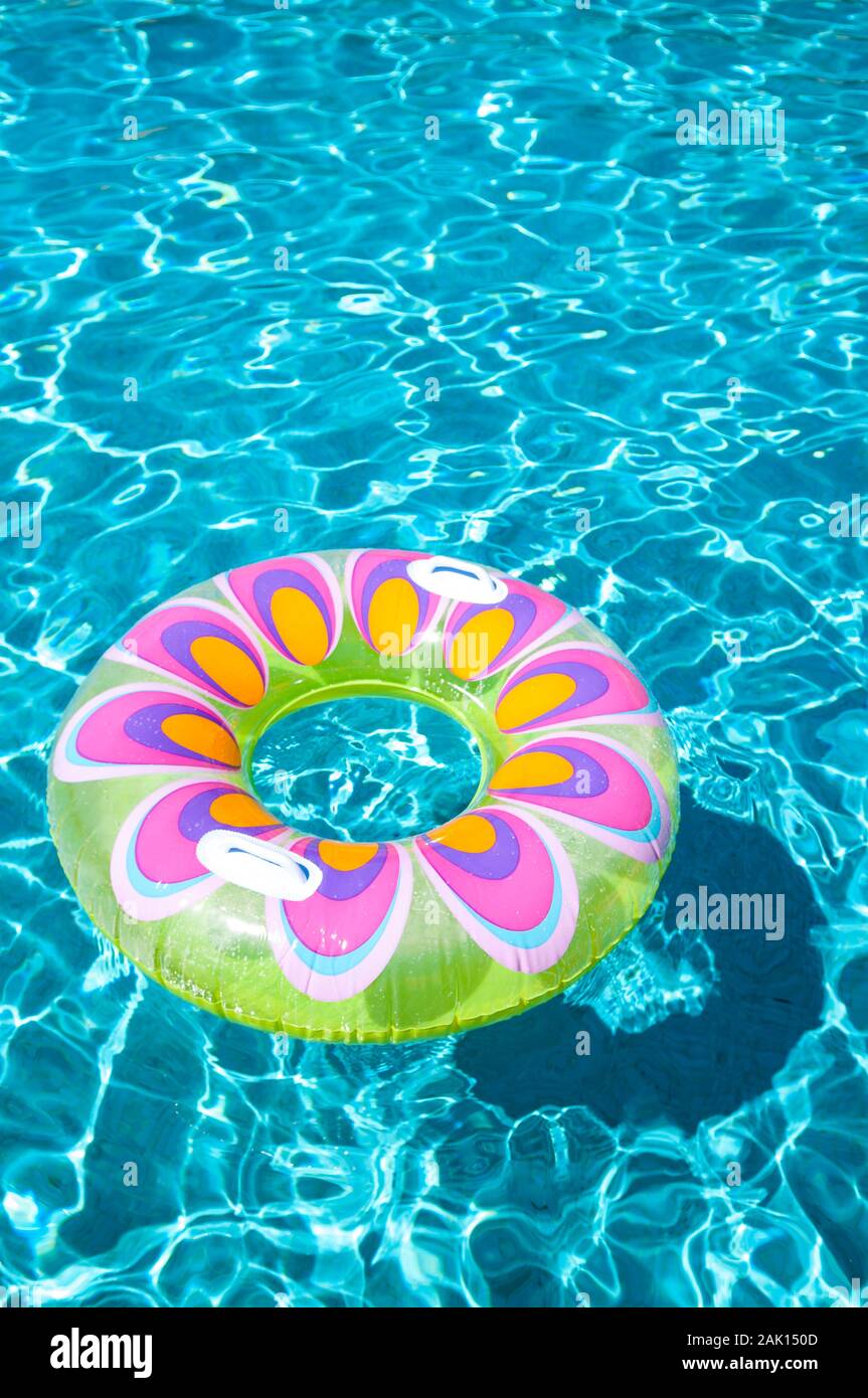 Brightly colored pool ring floating on dappled turquoise water in ...