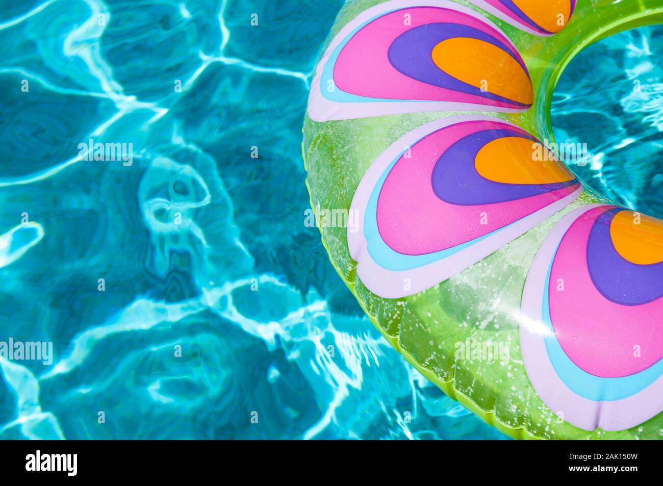 Brightly colored pool ring floating on dappled turquoise water in ...