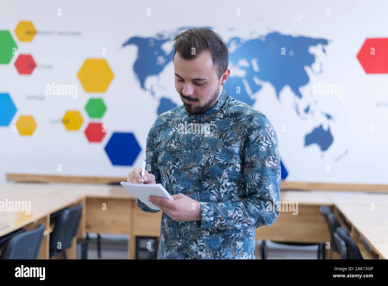 Male college student standing inside classroom and using tablet and ...