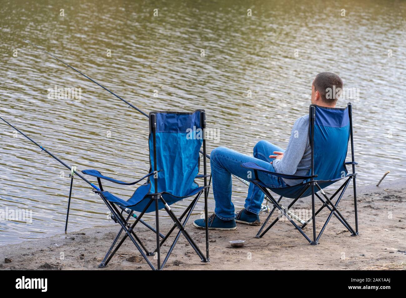 Man relaxing and fishing by lakeside Stock Photo - Alamy