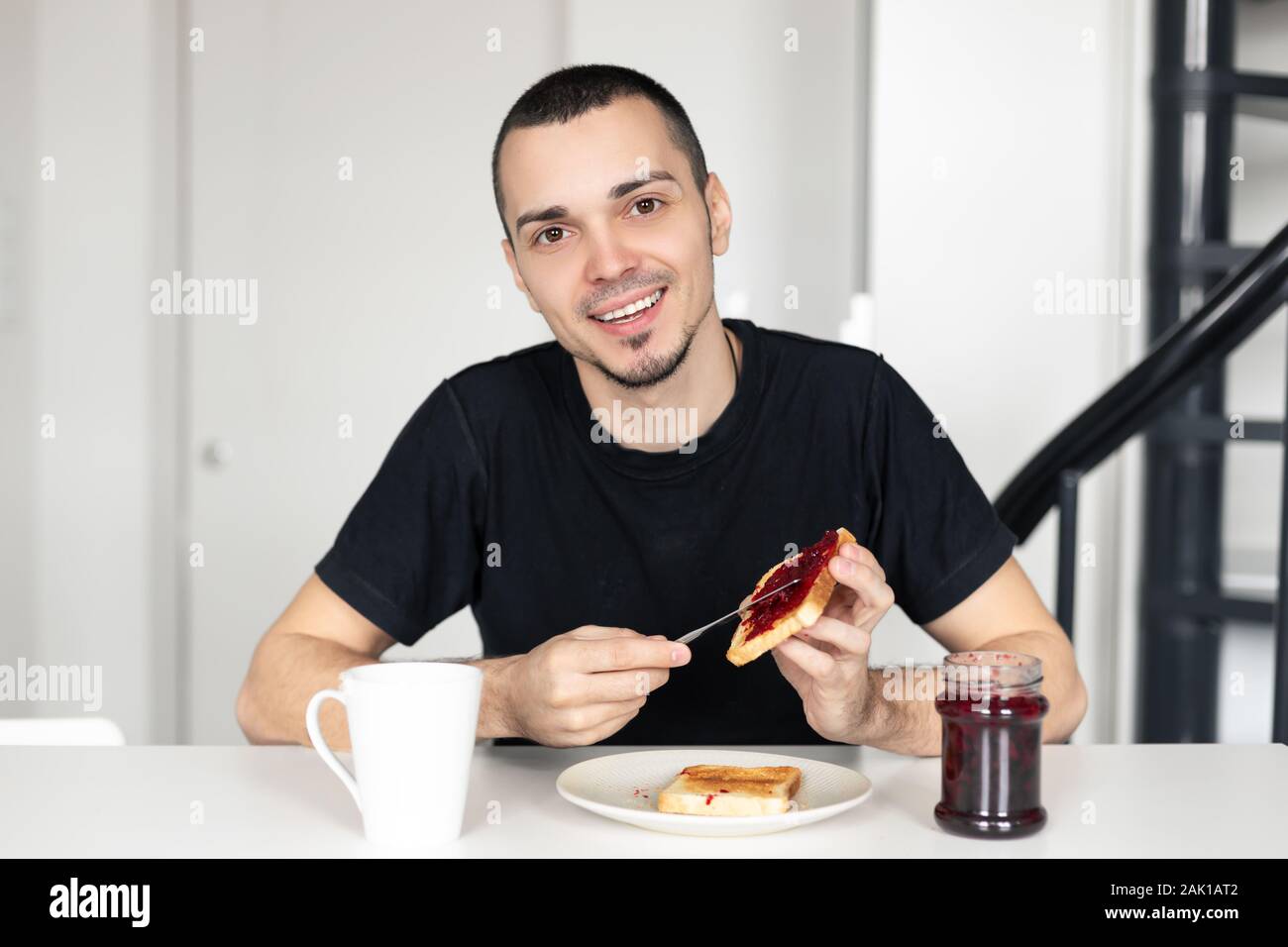 The guy has breakfast with toast with jam Stock Photo - Alamy