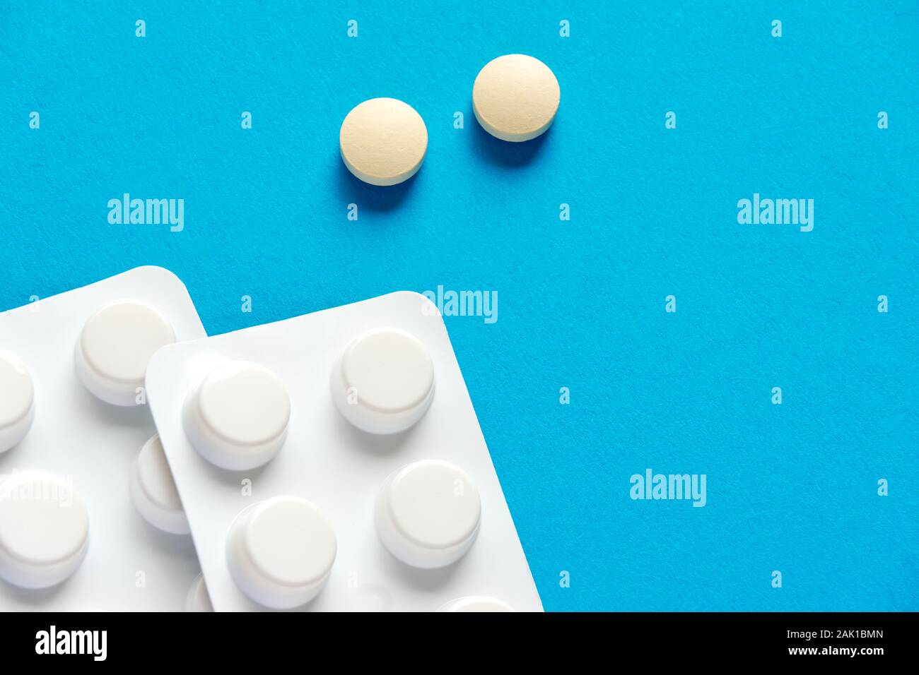 Two round and white prescription tablets or pills and pill strip on ...