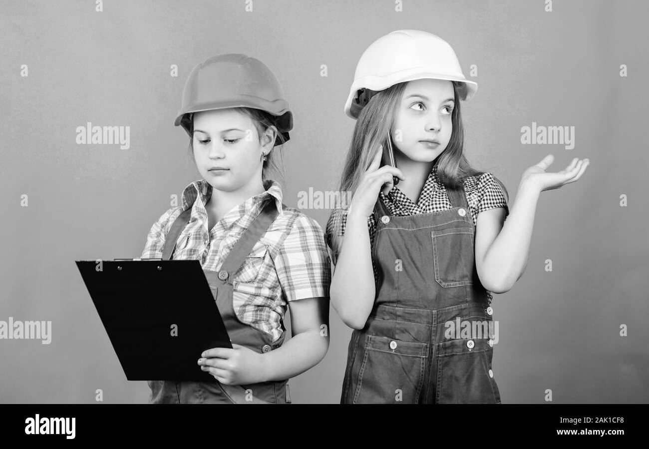 Little kids in helmet with tablet. small girls repairing together in ...