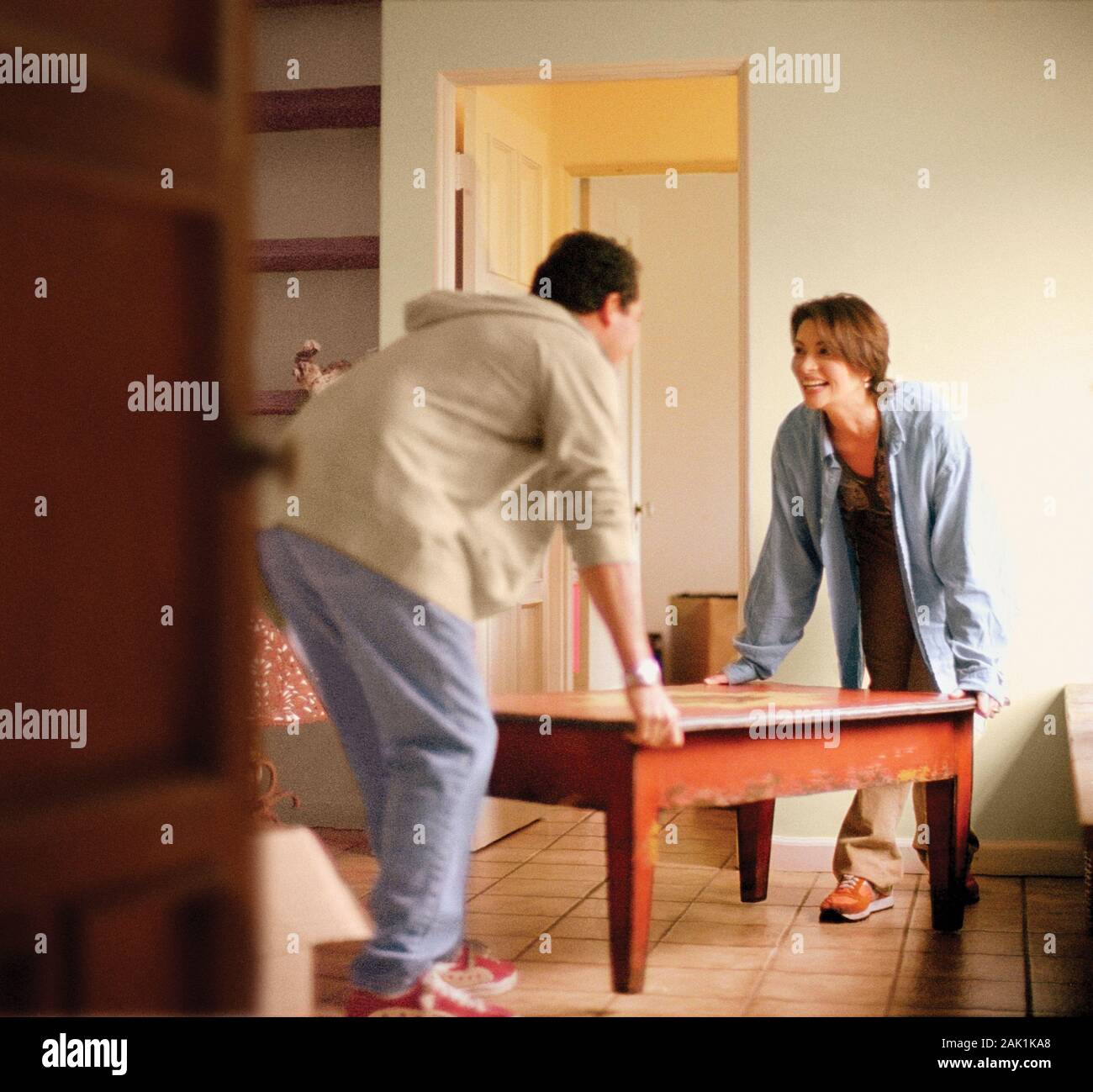 Couple moving table into empty room "80% Less Stock Photo - Alamy