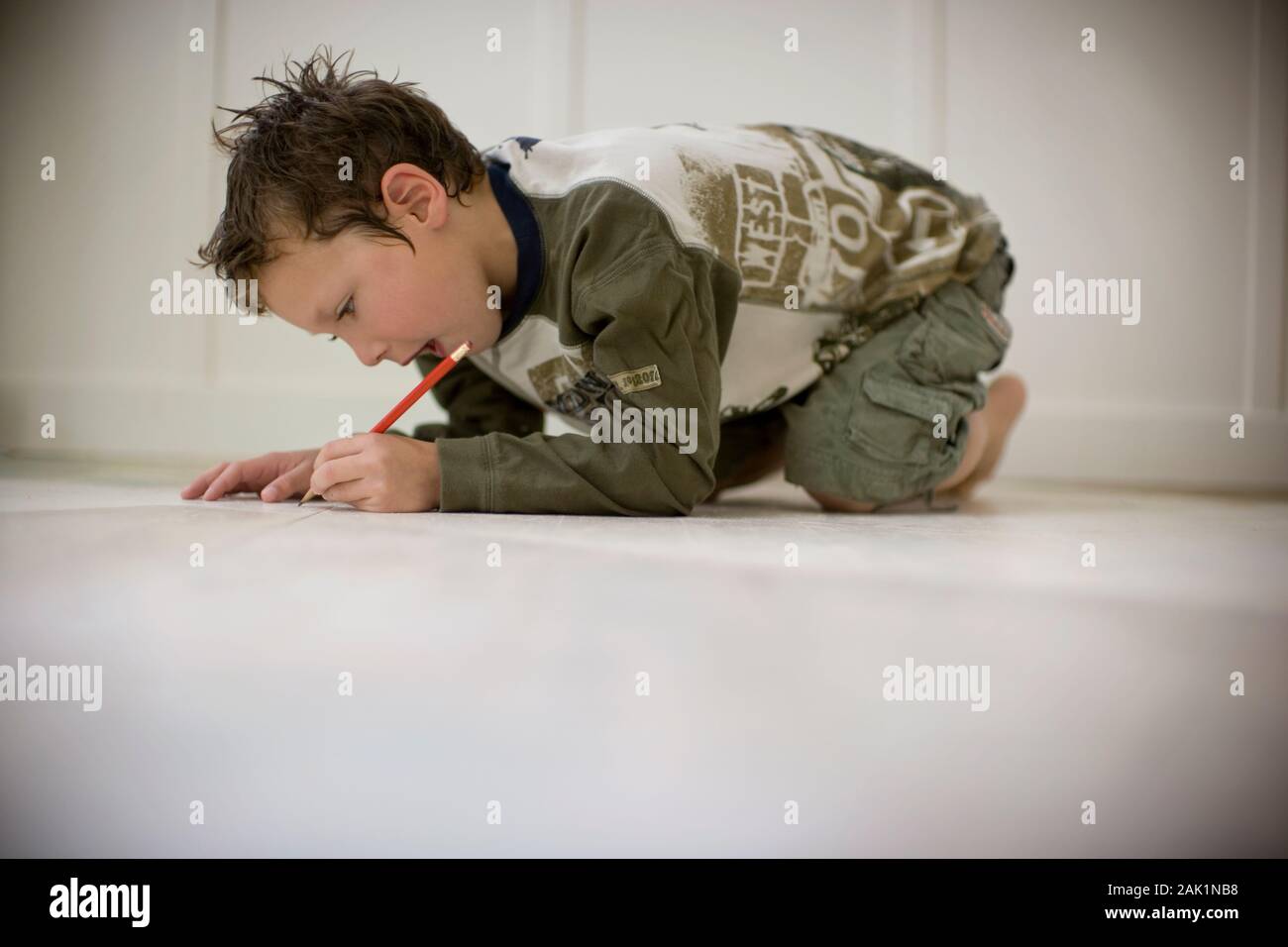 Young boy writing a note while kneeling on the floor Stock Photo - Alamy