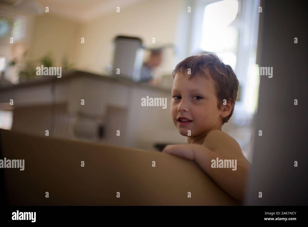 Portrait of a young boy sitting inside a box Stock Photo - Alamy