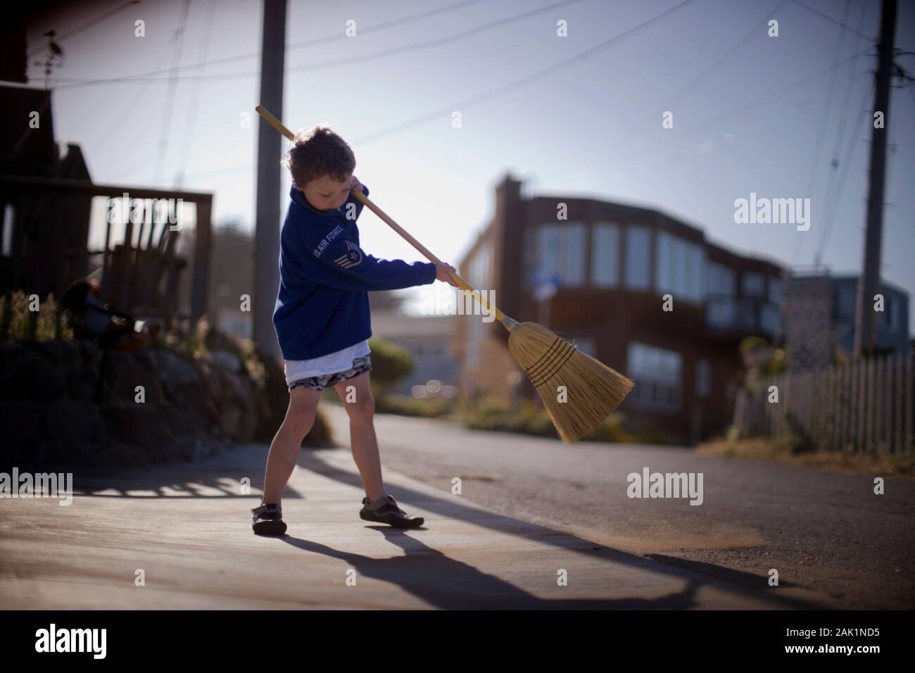 Young boy sweeping the pavement Stock Photo - Alamy