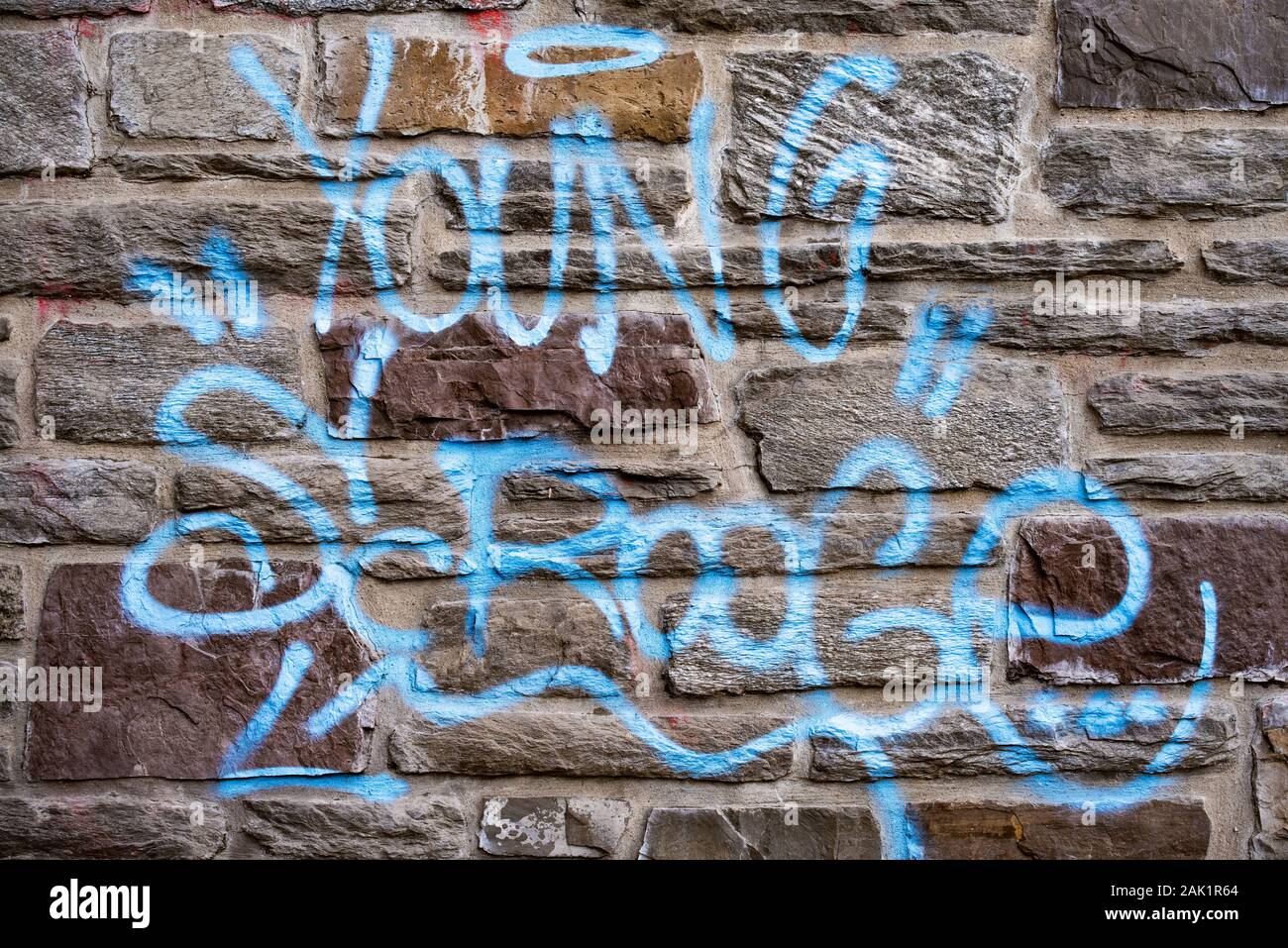 Detail of blue-lettered graffiti on a brick wall Stock Photo - Alamy