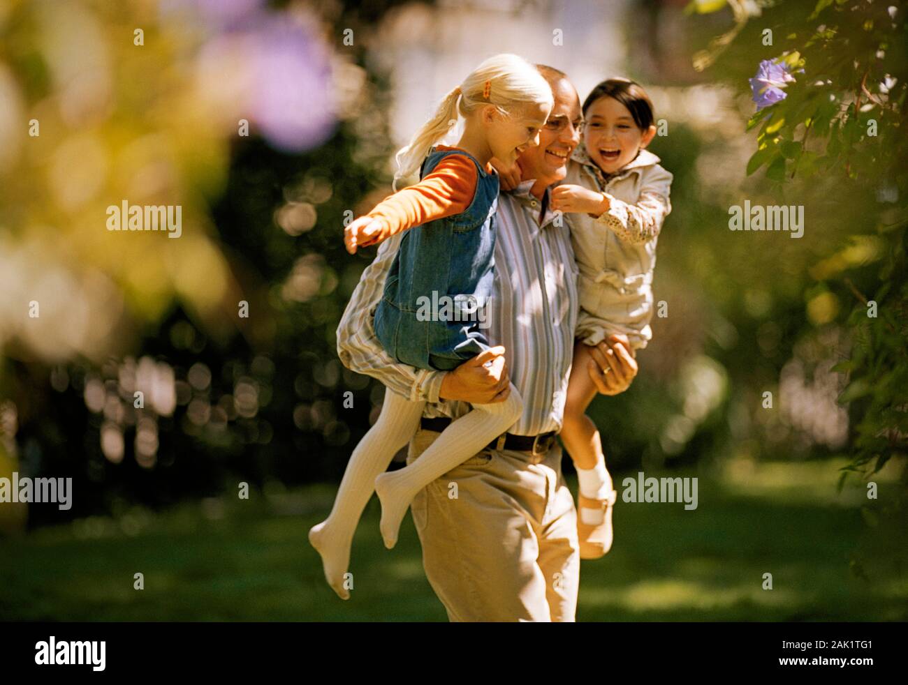 Mature carrying his two daughters Stock Photo - Alamy