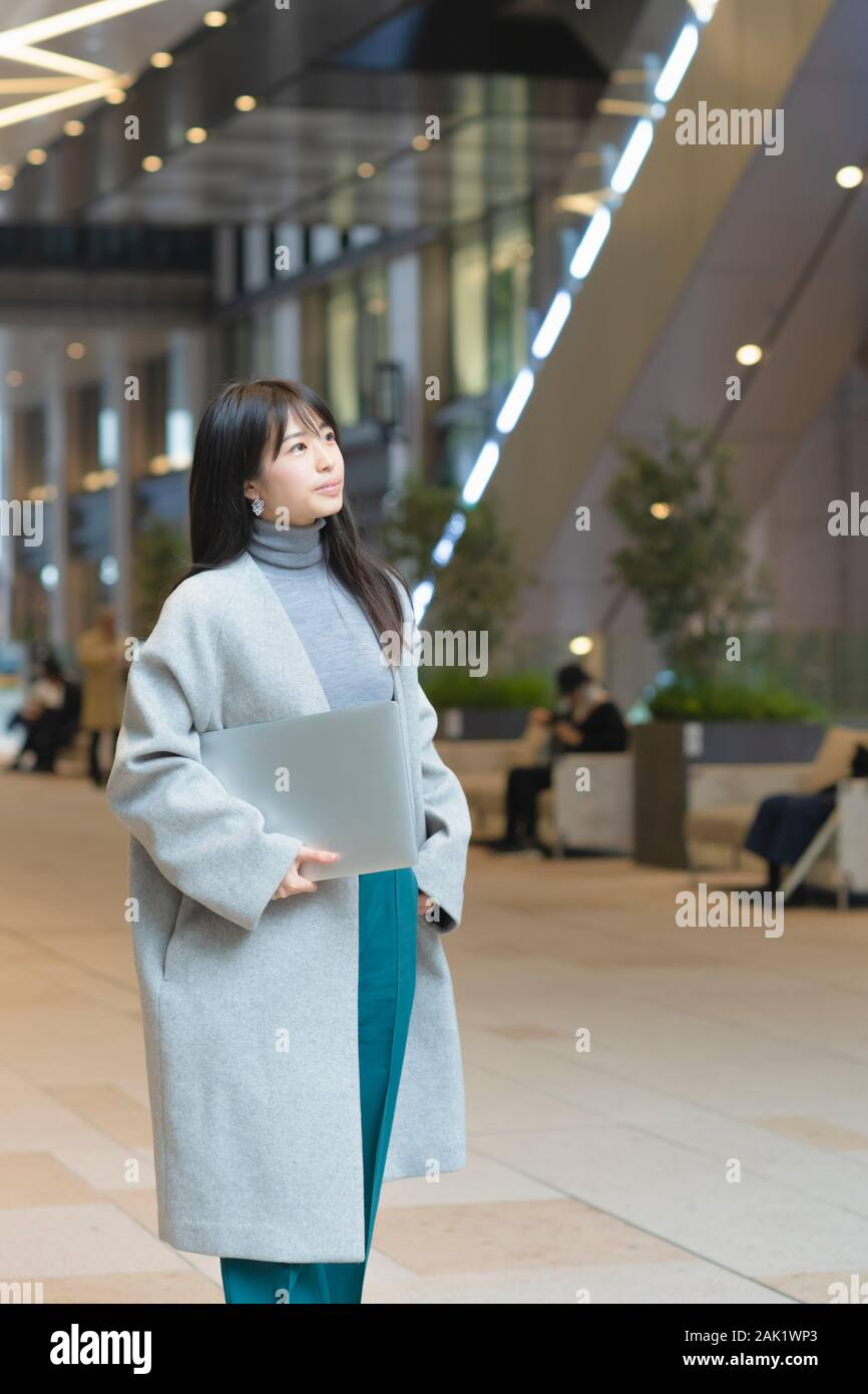 Woman holding laptop under the arm Stock Photo - Alamy