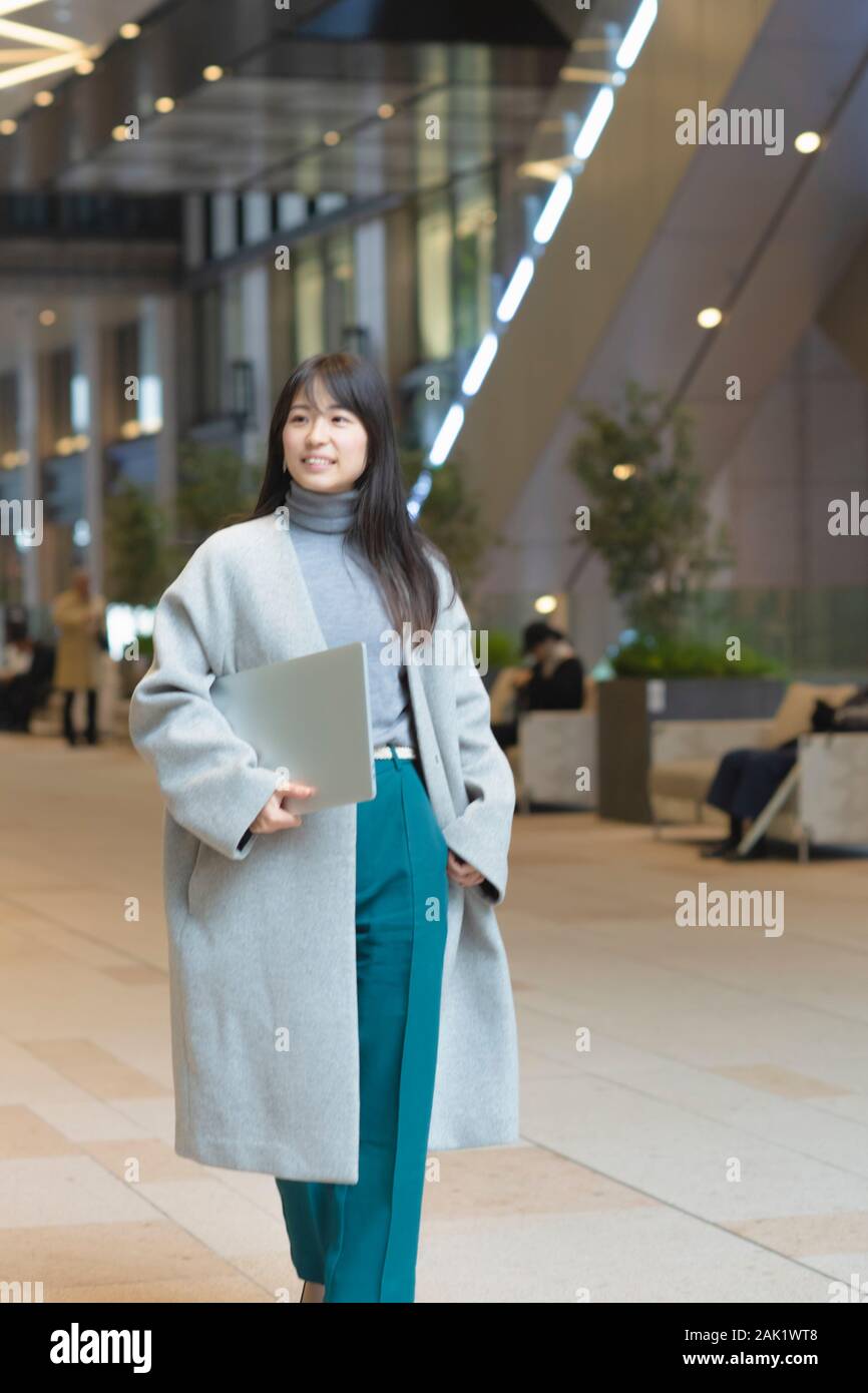 Woman holding laptop under the arm Stock Photo - Alamy
