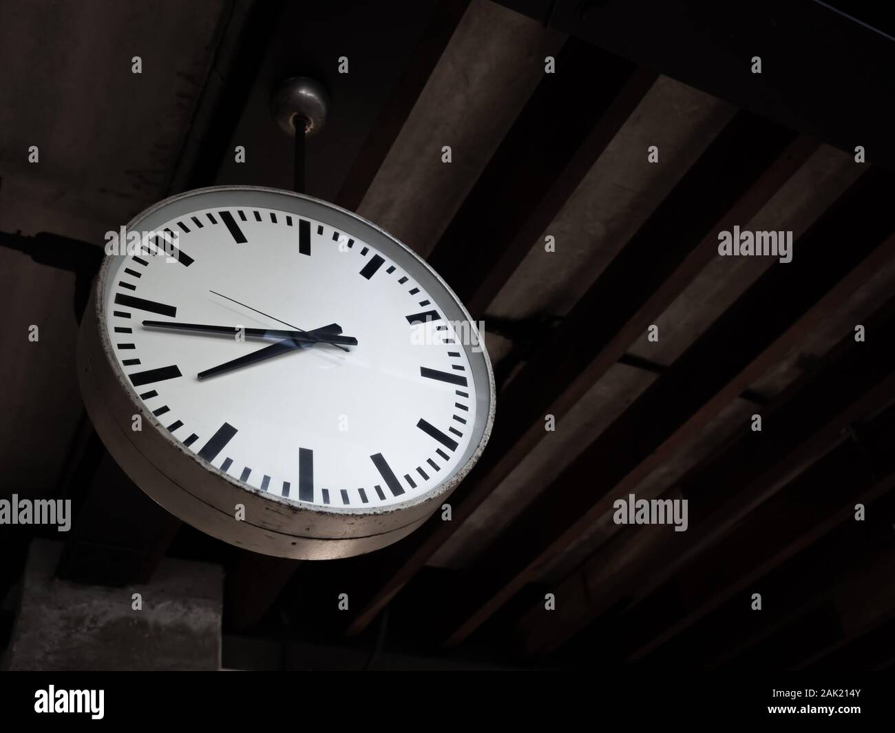 Simple old round clock hanging from wooden ceiling decoration in cafe ...