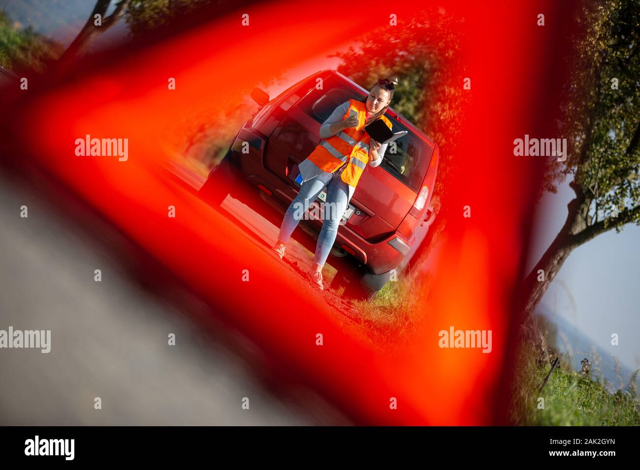 Annoyed young woman in a road distress situation - setting up a warning ...