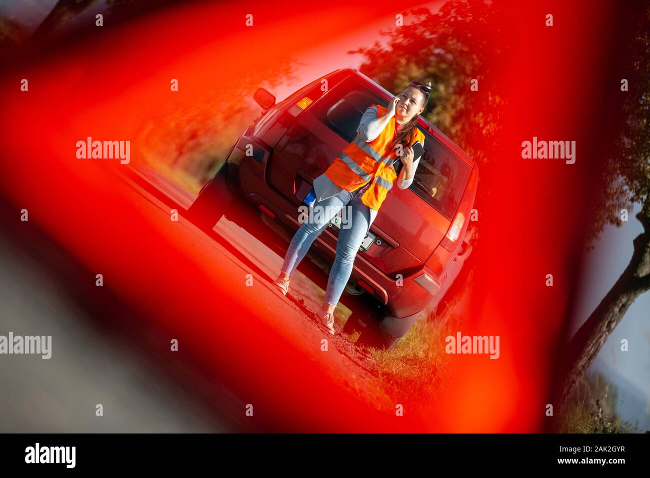 Annoyed young woman in a road distress situation - setting up a warning ...