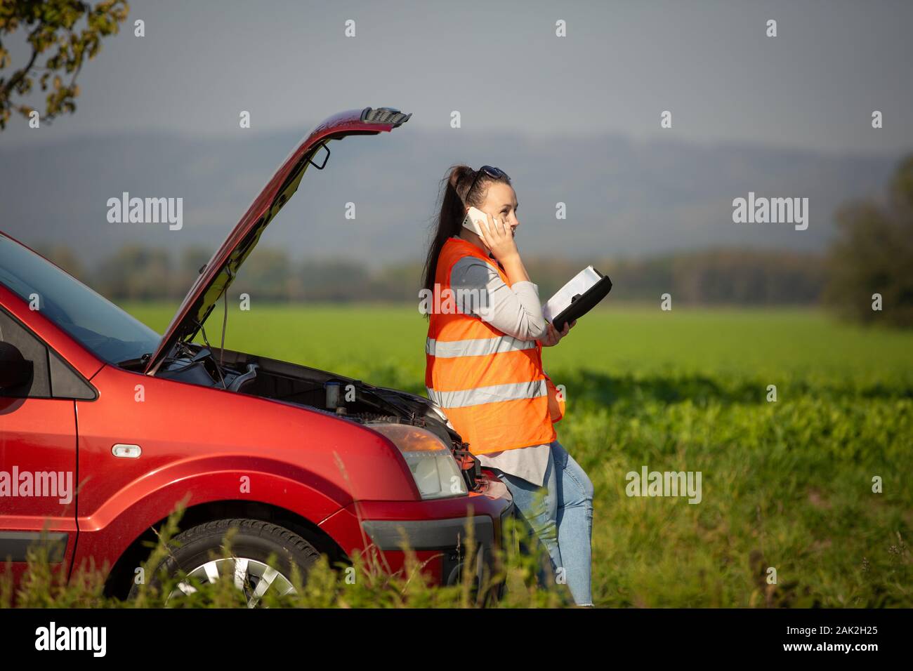 Annoyed young woman in a road distress situation - setting up a warning ...