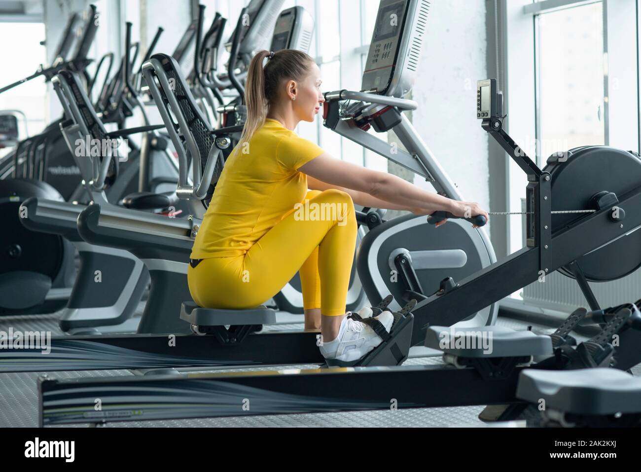 Side view of fit young women using rowing machine in health club Stock ...