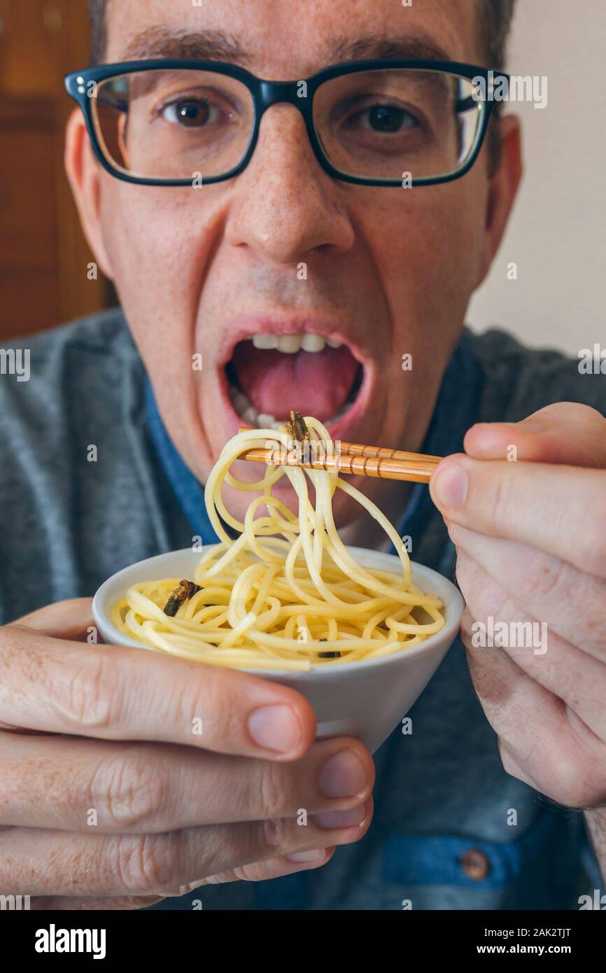 Man eating spaghetti and crickets Stock Photo - Alamy