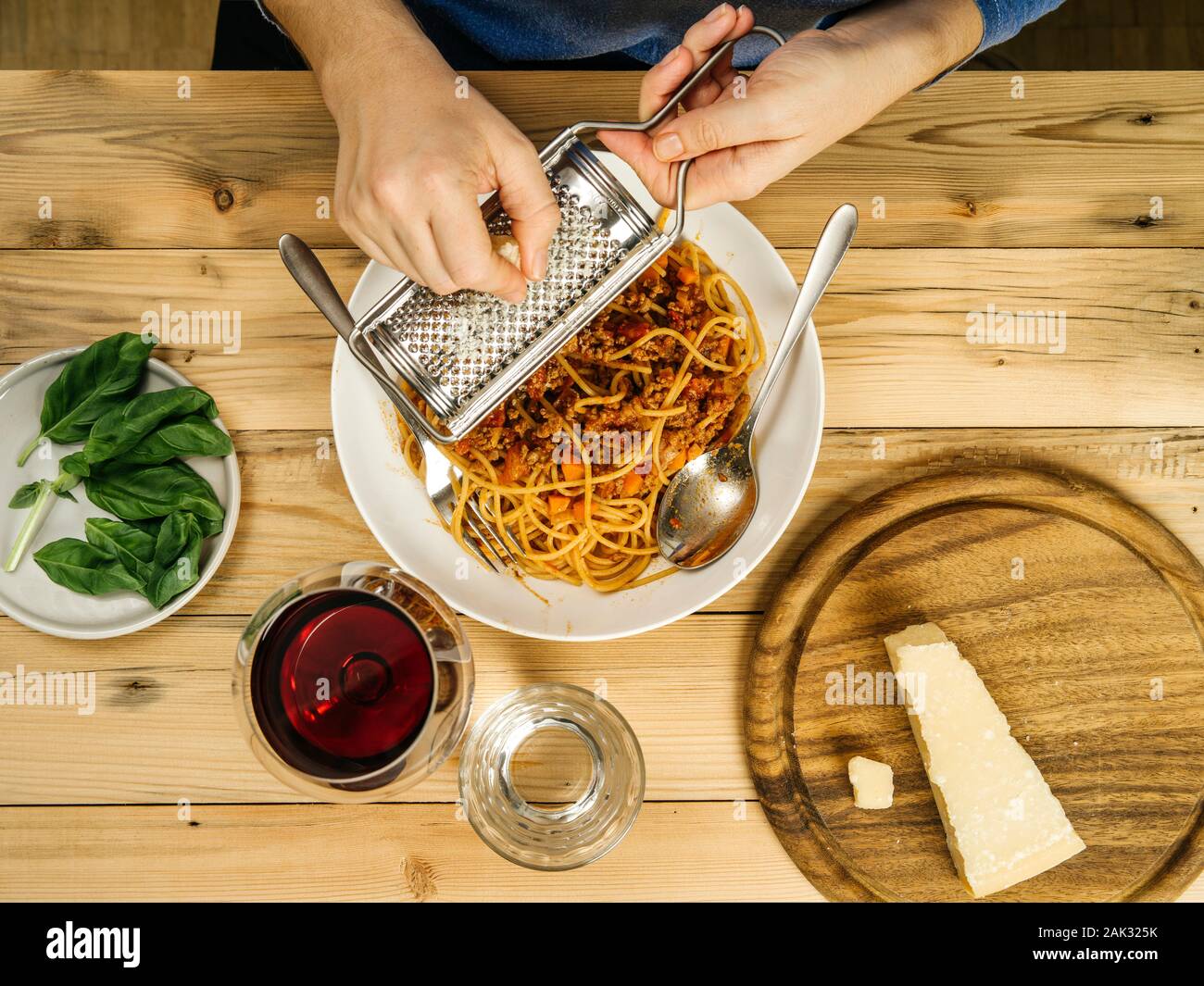 Photo of a woman grating parmesan cheese over a bowl of traditional ...