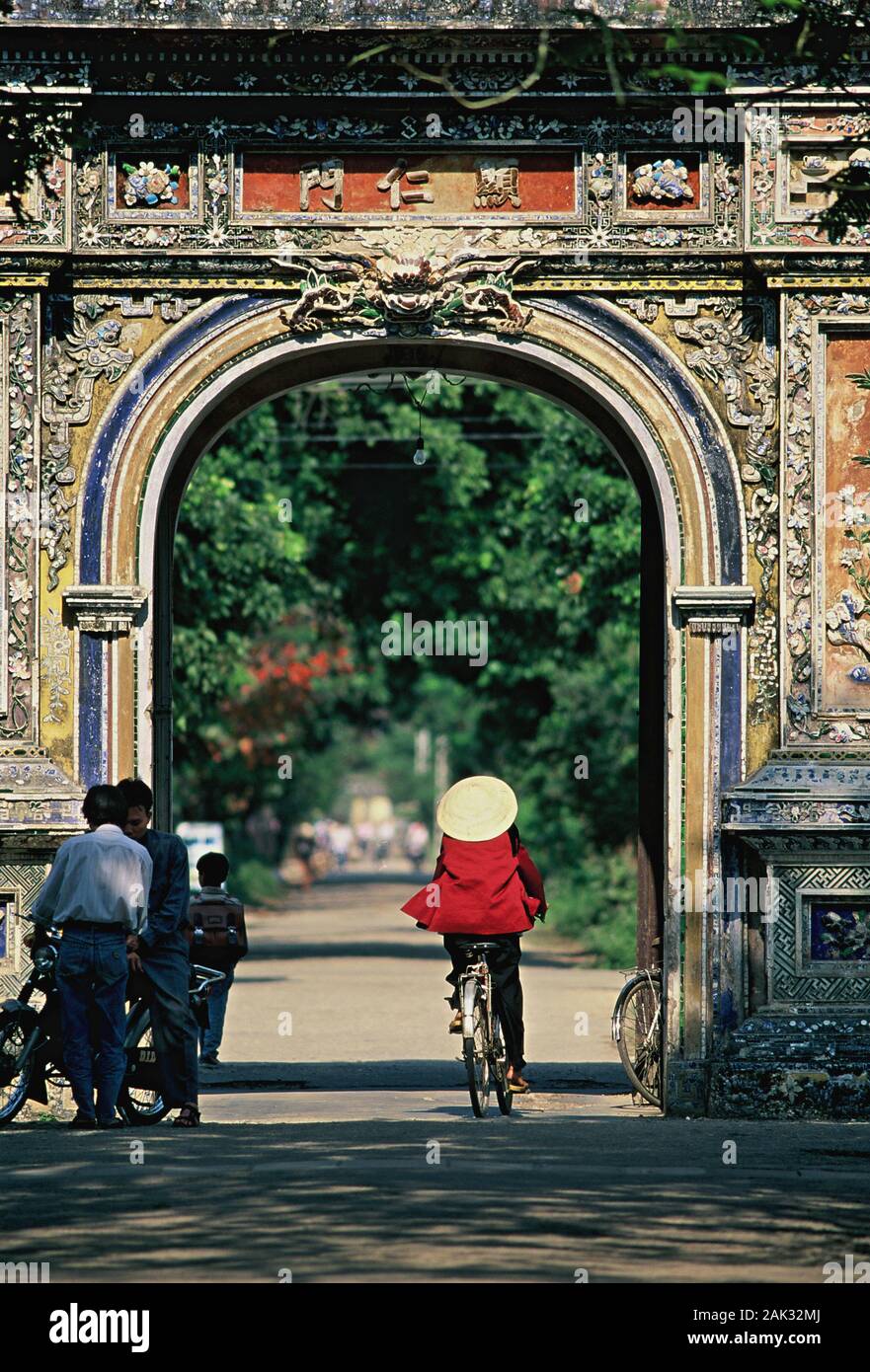 A cyclist passing the gate of the 19th century built citadel in Hue, a ...