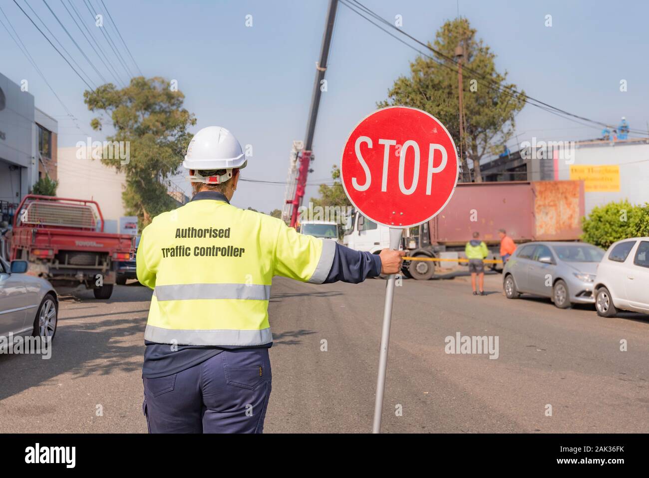 An authorised traffic controller (stop go person) holds up vehicles ...