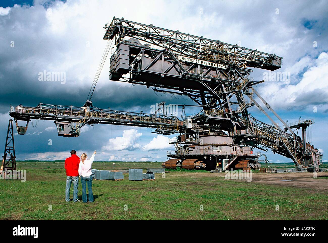 A couple standing in front of a huge bucket wheel in the open-air ...