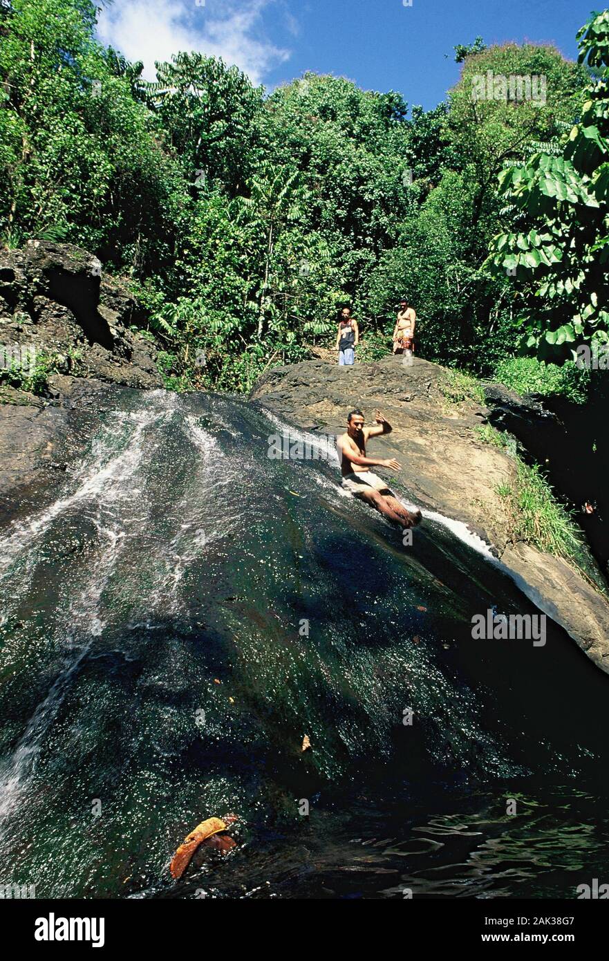 Tourists sliding down the Papasea Rocks on the island of Upolu in Samoa ...