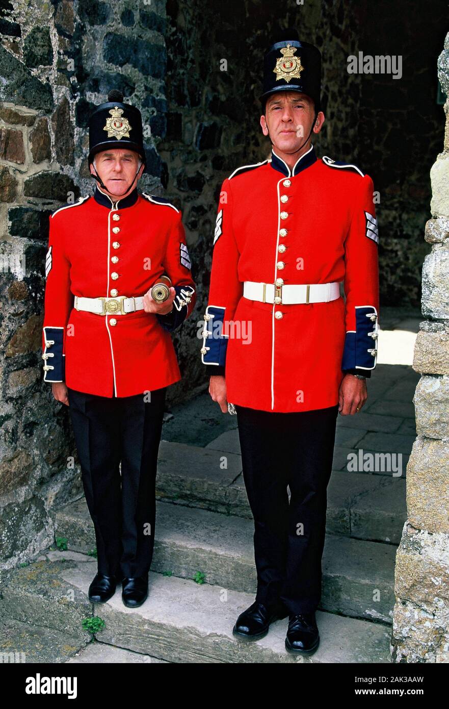 Two cannoneers dressed in traditional uniforms guarding an entrance of ...