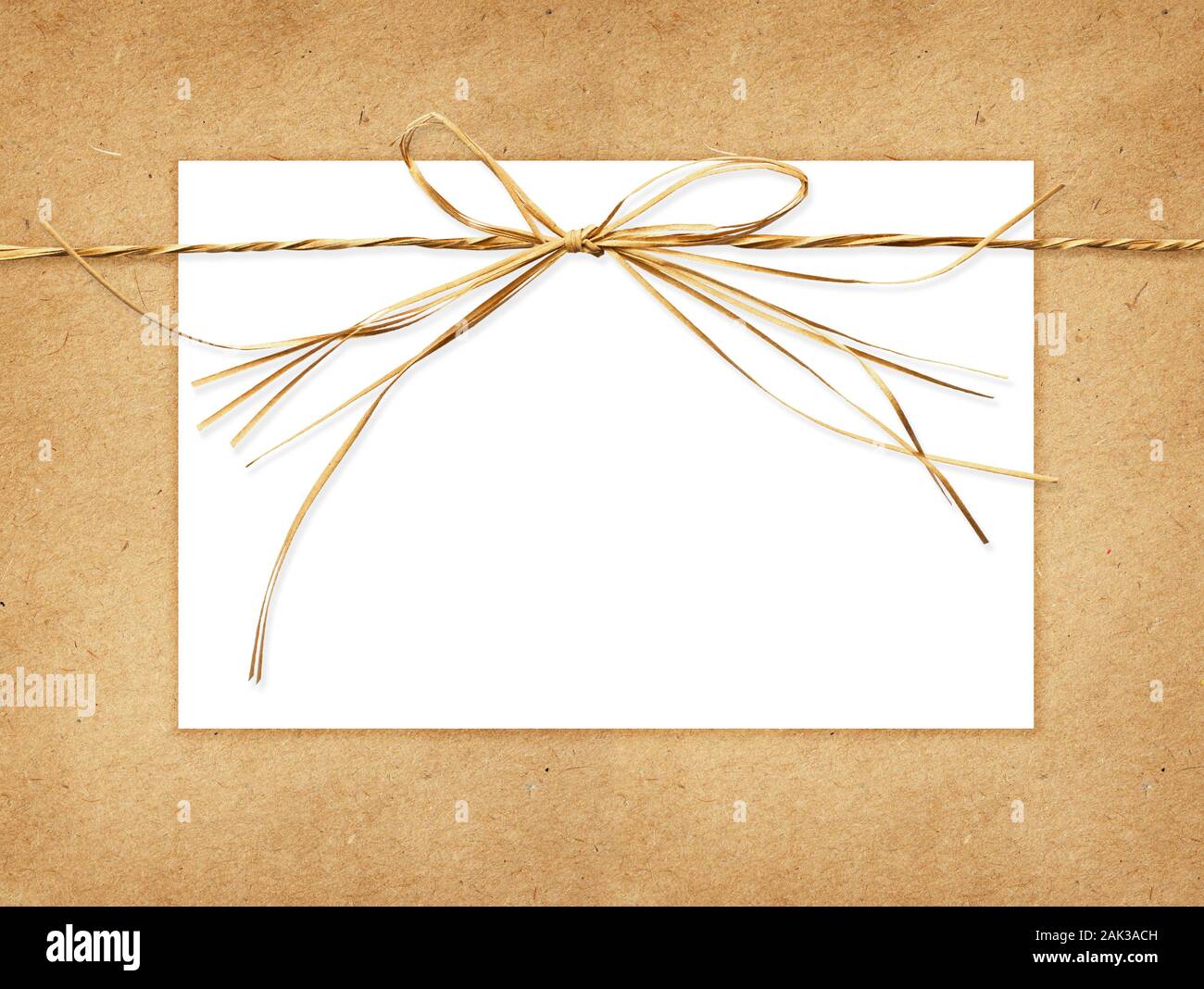 Beige raffia bow and a card tied on craft paper background Stock Photo ...