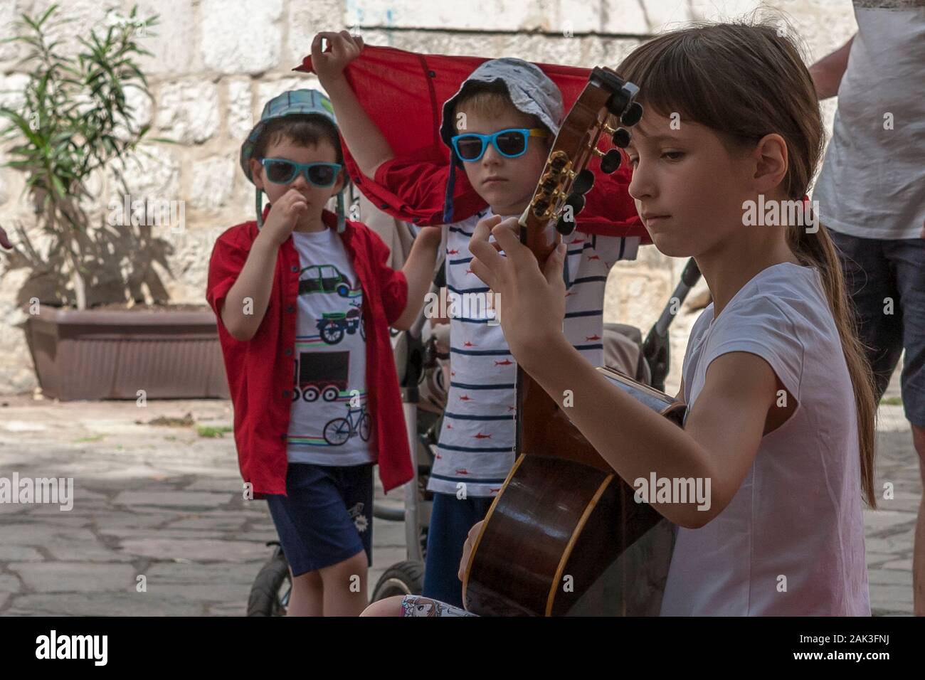 Little girl busking on a guitar, watched by other children, Pjaca od ...