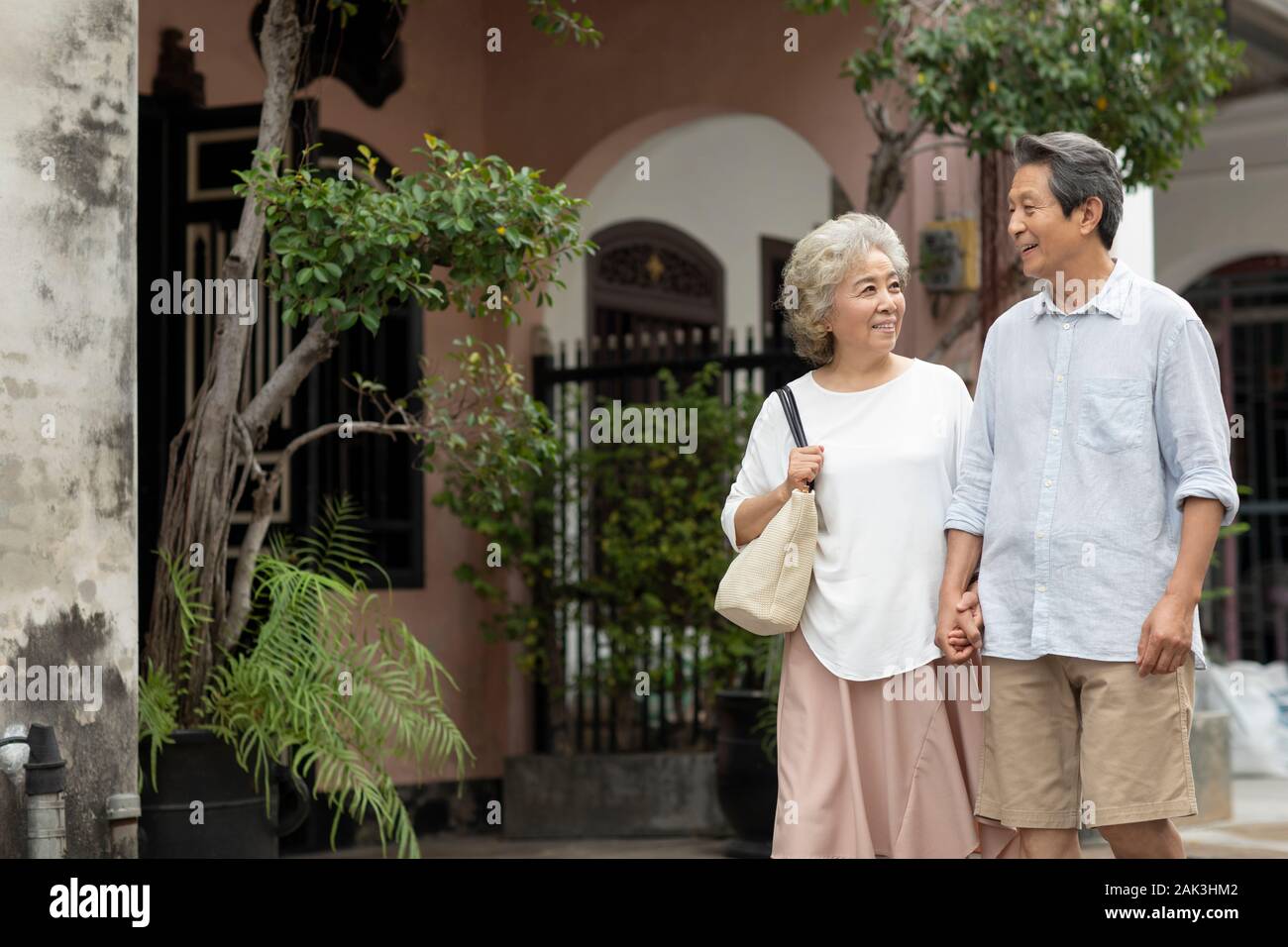 Happy senior Chinese couple walking on street Stock Photo - Alamy