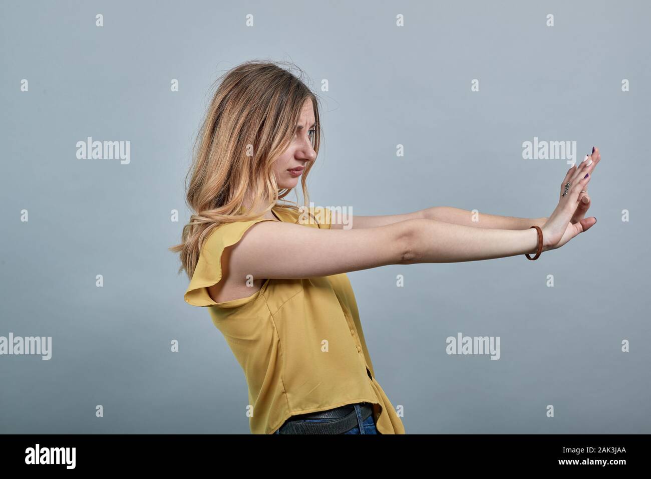 Disappointed young woman staying sideways, doing stop gesture with ...