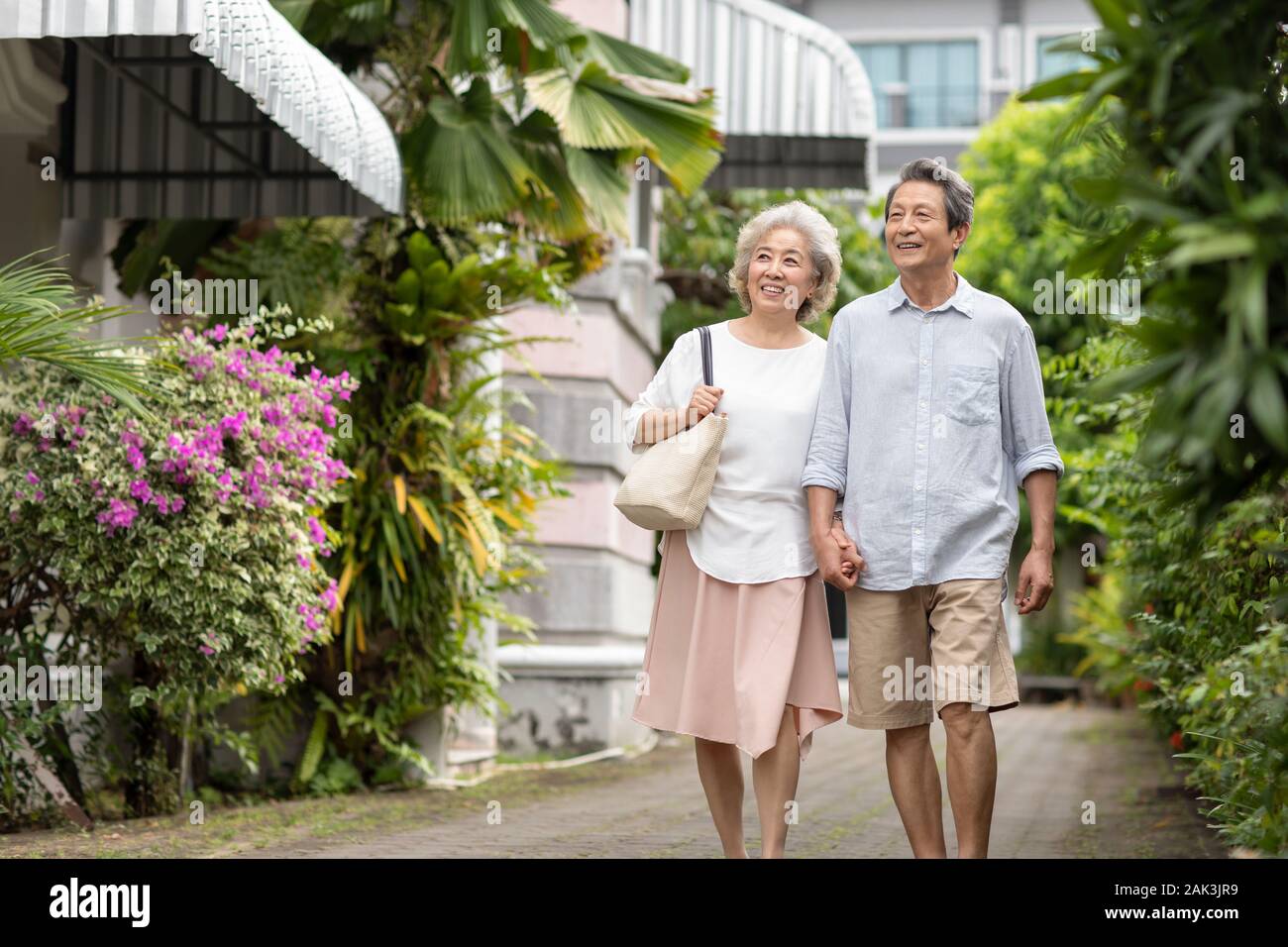 Happy senior Chinese couple holding hands and walking together Stock Photo - Alamy