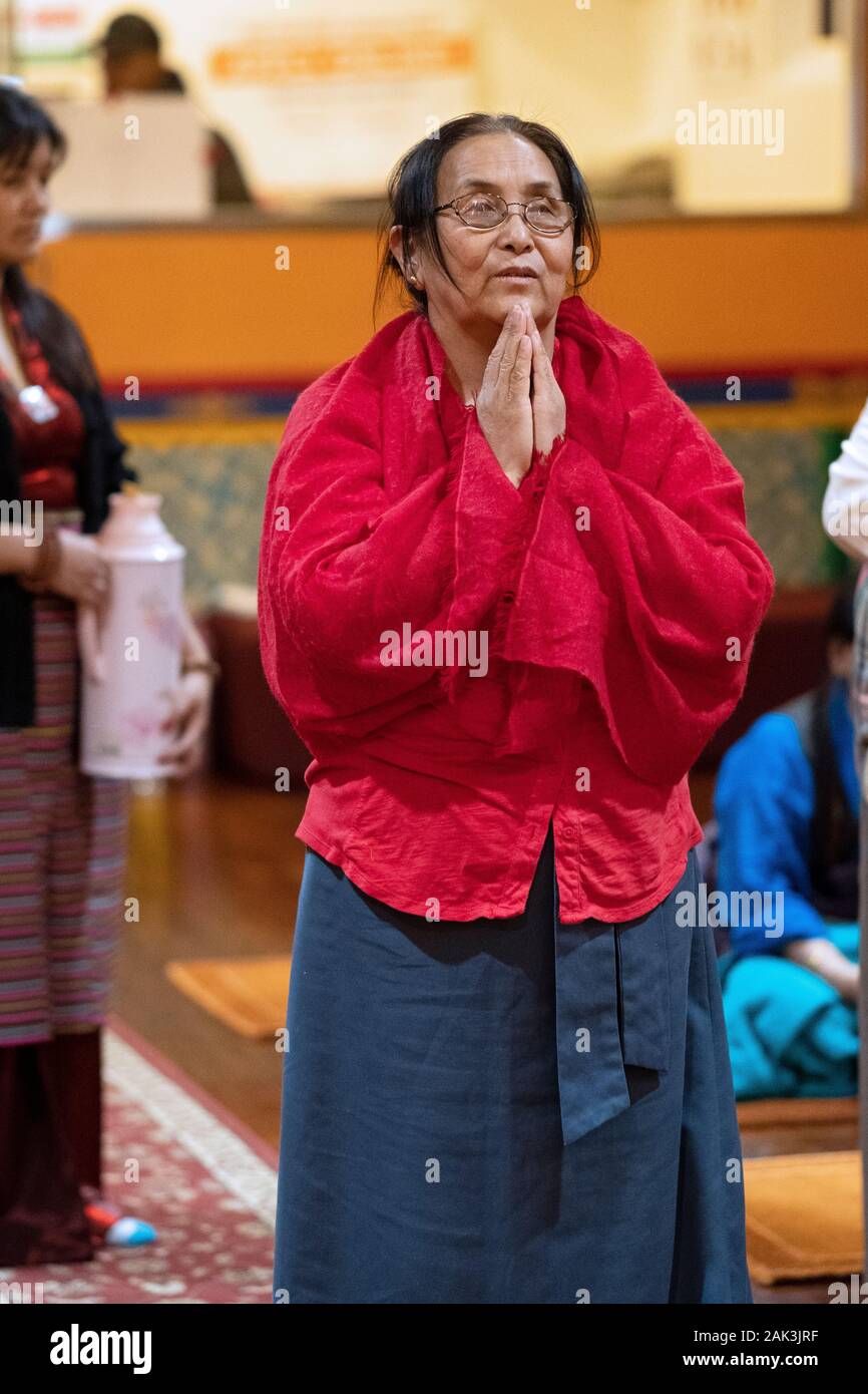 A devout Buddhist woman praying and meditating as she enters a temple ...