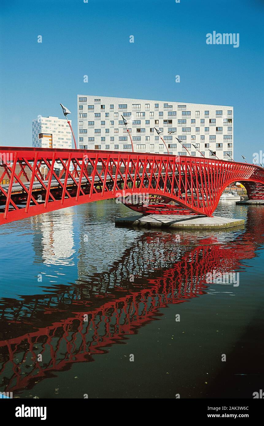 A modern bridge leads across a wide canal in the Amsterdam district of ...