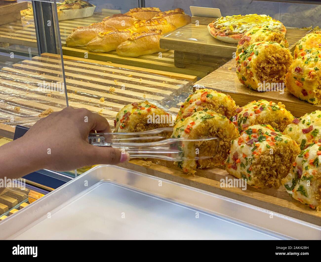 Customer's hand picking pork floss roll by tongs at bakeshop Stock ...