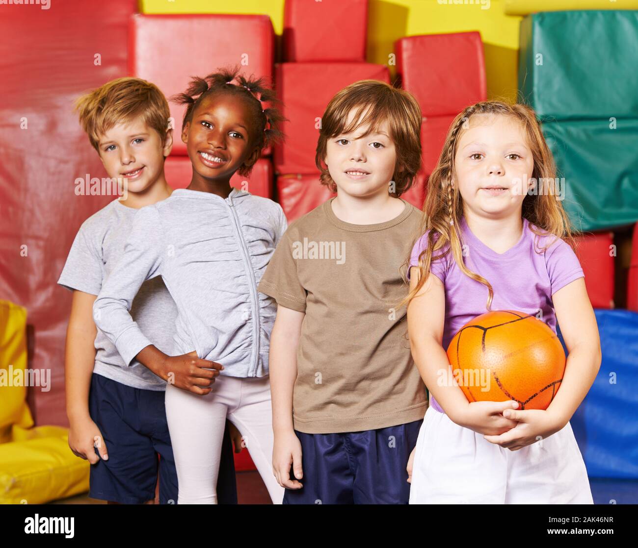 Happy group of kids is standing with a ball in preschool Stock Photo ...