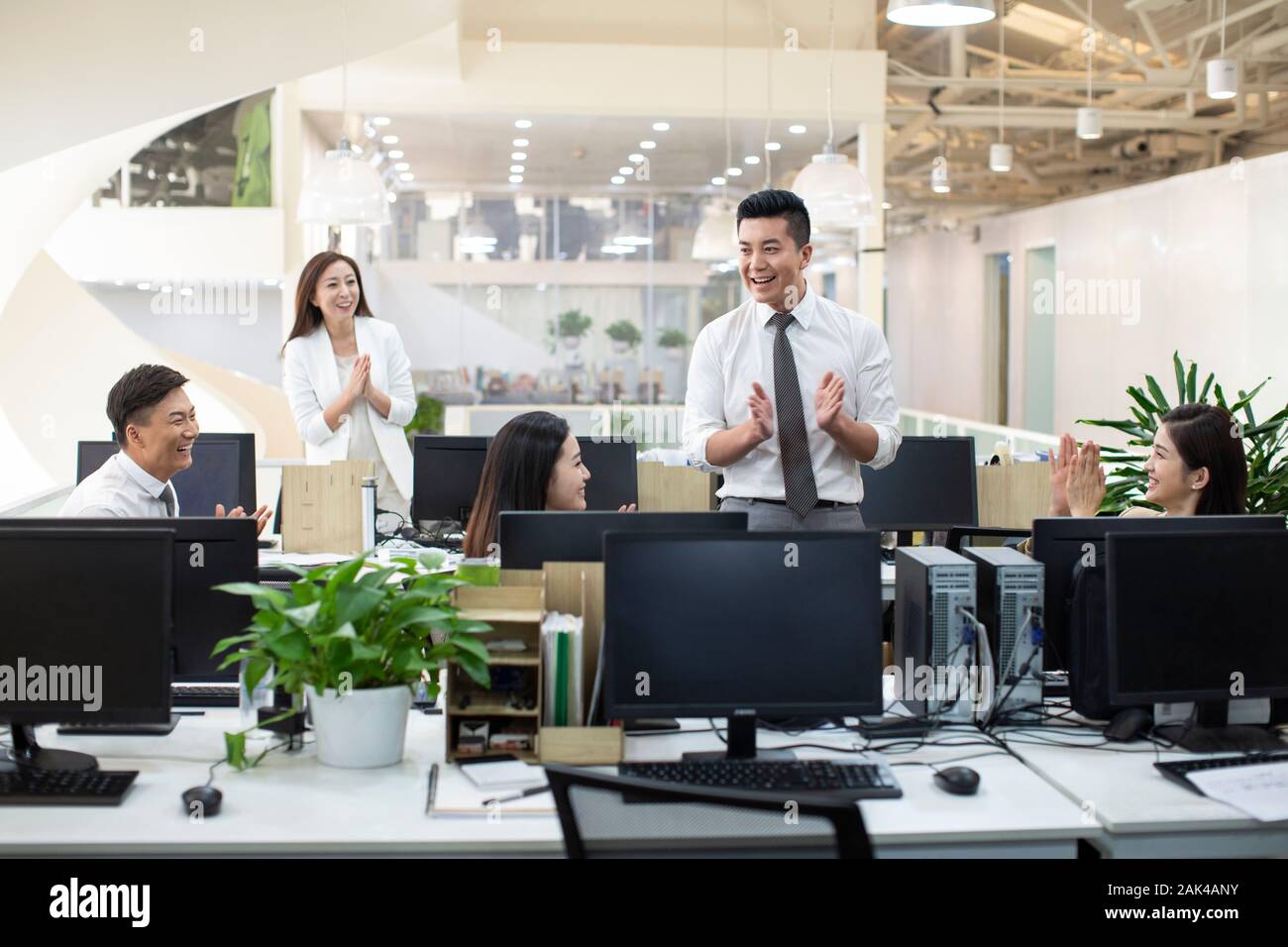 Chinese business people clapping hands in office Stock Photo - Alamy