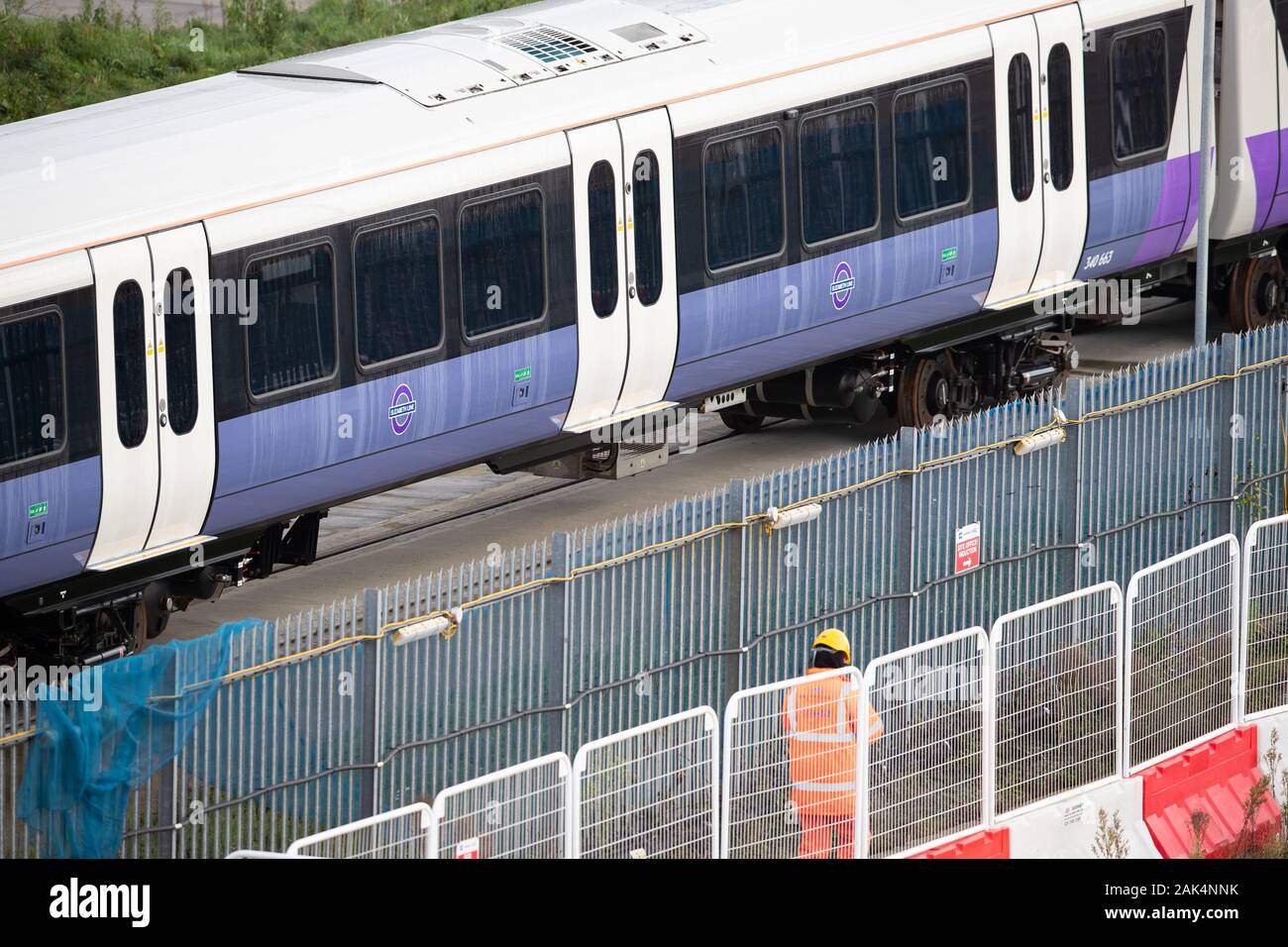A worker wearing high visibility clothing passes crossrail trains ...