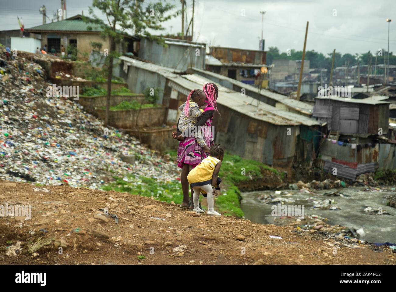 Young Kenyan children stand looking towards Mathare river and slum ...