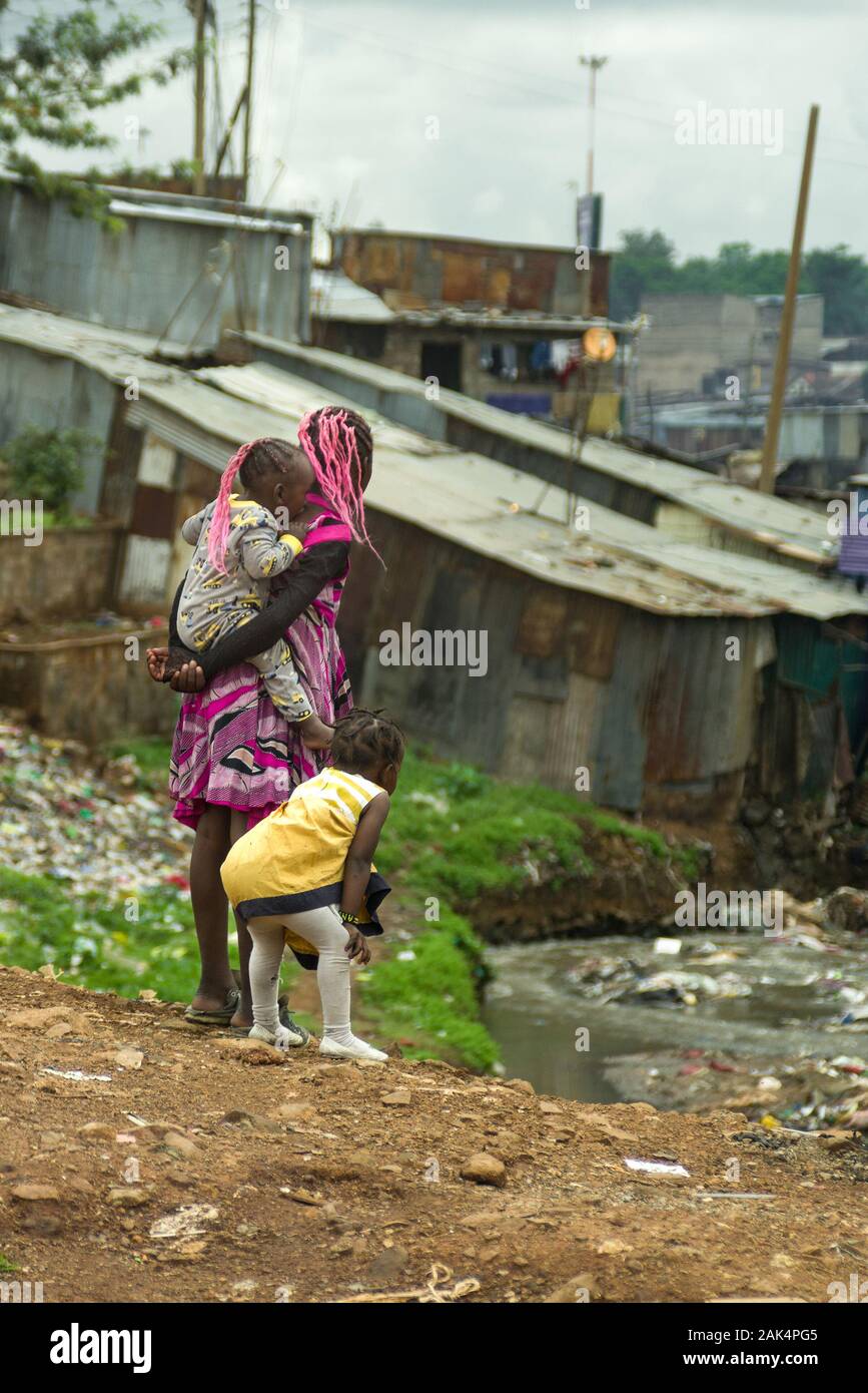 Young Kenyan children stand looking towards Mathare river and slum ...