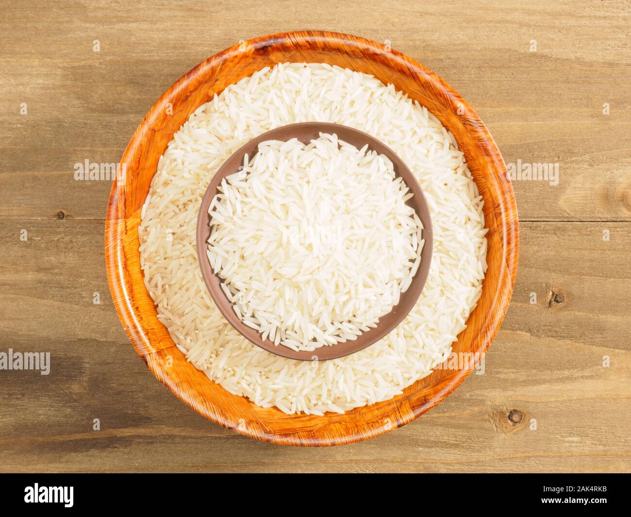 Rice in bowl and clay plate on brown wooden background. Indian cuisine ...