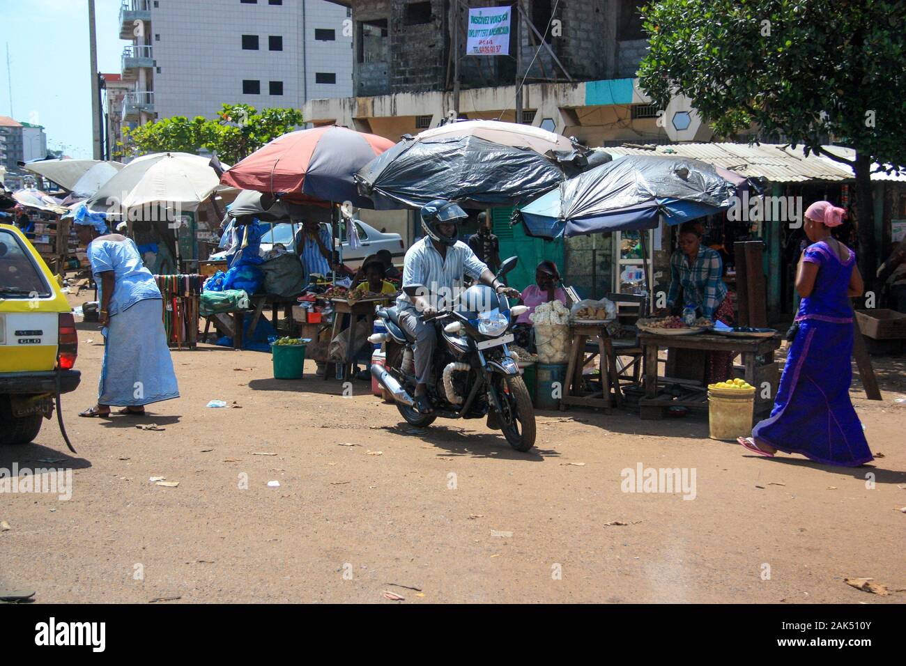 People at the market on the side of the dirt road in Conakry, Guinea ...
